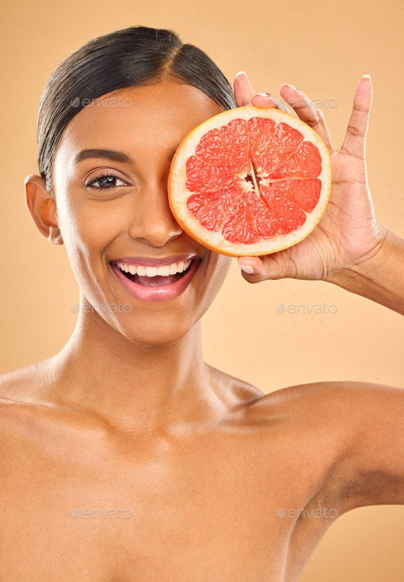 Face smile, skincare and woman with grapefruit in studio isolated on a brown background ...