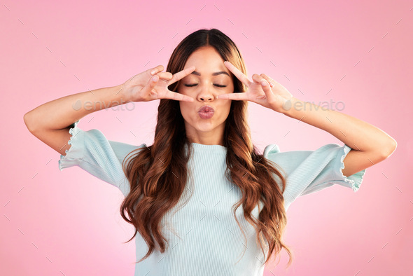 Peace sign, kiss and face of woman in studio for happiness ...