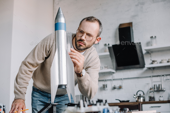 handsome engineer modeling rocket and measuring with ruler at home ...
