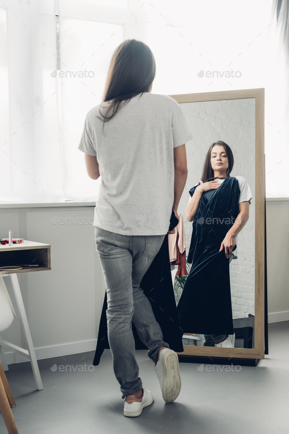 young transgender woman with dress looking at mirror at home Stock ...