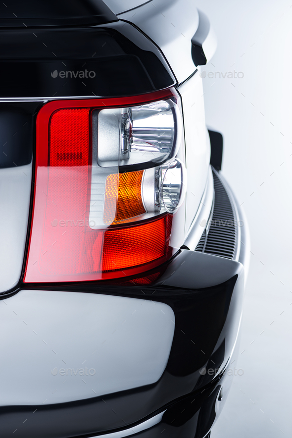 Close up view of rear headlight of luxury black car on grey backdrop ...
