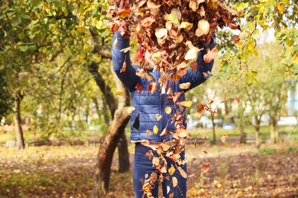 autumn people. Teen girl raising hand and throwing leaves. Many flying ...