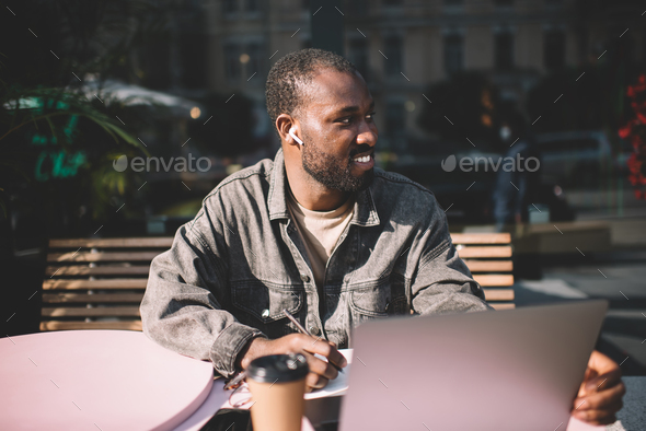 Millennial hipster guy with laptop computer and textbook enjoying music ...