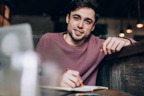 Skilled male blogger with notepad and digital netbook posing in ...