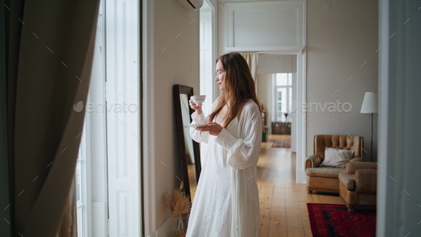 Calm woman drinking tea at morning home interior. Tender lady watching ...