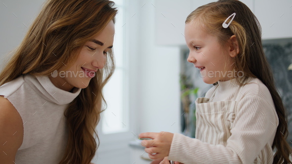 Cute kid touching mother face kitchen portrait. Laughing mom bonding to ...