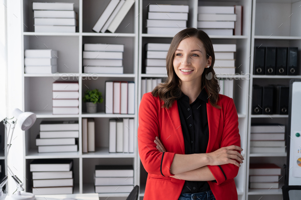 Portrait of beautiful caucasian businesswoman wearing red suit working ...