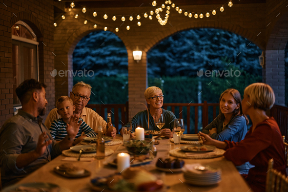 Happy extended family having dinner at dining table on a terrace. Stock ...