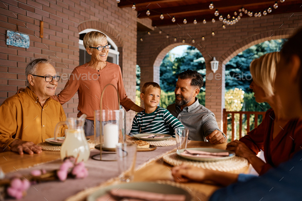 Happy extended family talking while gathering at dining table on a ...