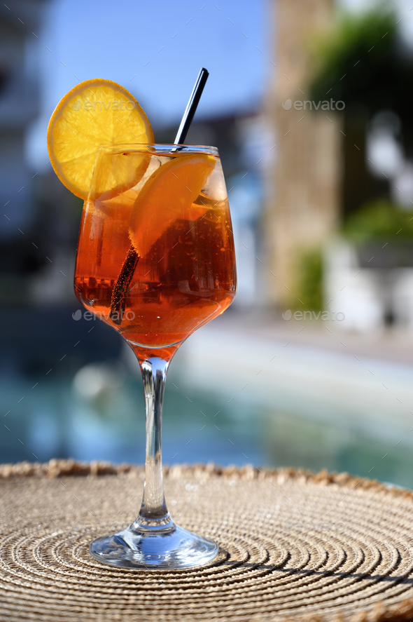 Red cocktail with orange slice and ice near a hotel pool Stock Photo by ...