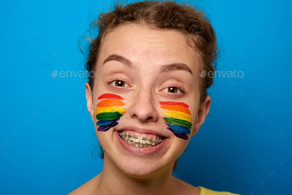 Girl with pride flag painted on her cheeks smiling Stock Photo by ...