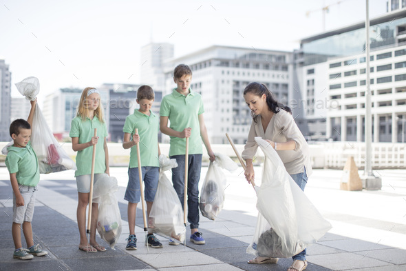 Group of volunteering children collecting garbage with litter sticks ...