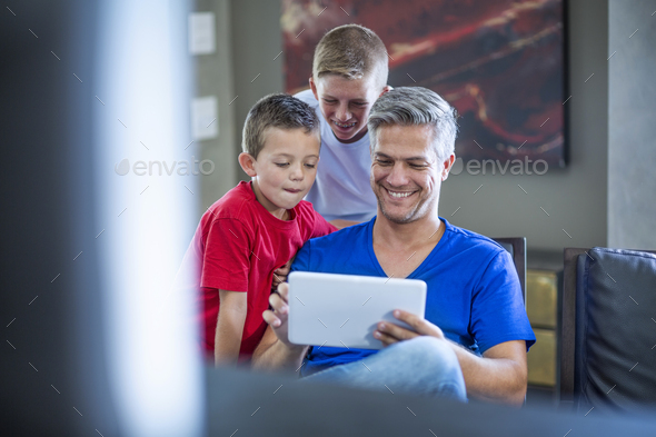 Children looking with their father on digital tablet Stock Photo by ...