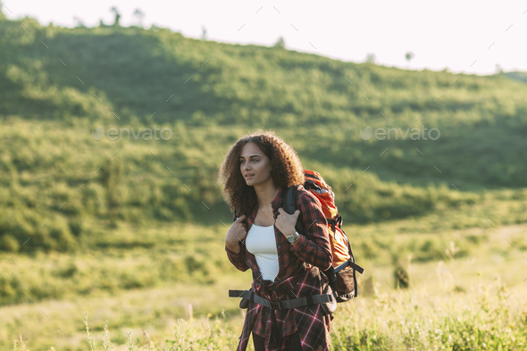 Teenage girl with backpack hiking in nature Stock Photo by westend61