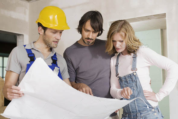 Young couple and construction worker looking at construction plan Stock ...