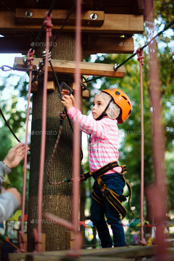 Girl climbing a rope trail in an adventure rope park. Stock Photo by ...