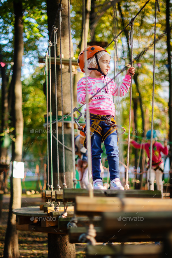 Girl climbing a rope trail in an adventure rope park. Stock Photo by ...