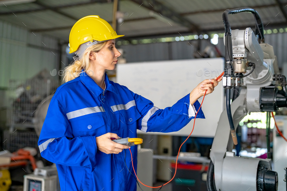 Engineer inspecting automatic AI robot arm and machines in factory ...