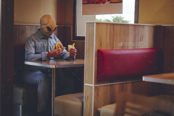 One man with alien mask eating alone inside a fast food store bad food ...