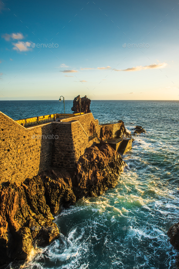 Rocks at Ponta do Sol, Madeira beach with promenade on cliffs. Sunset ...