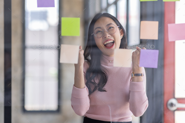 Young Asian woman Creative team use post it notes to share idea sticky ...