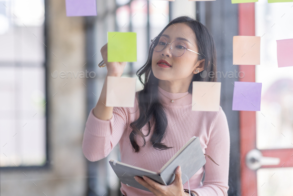 Young Asian woman Creative team use post it notes to share idea sticky ...