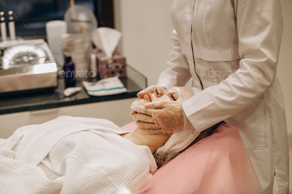 Cosmetologist applying mask on woman's face in spa salon, top view ...