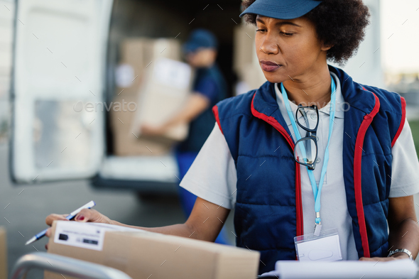 Black female deliverer checking package data before the shipment. Stock ...