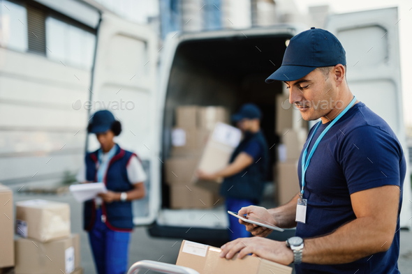 Young worker using touchpad while making a delivery in the city. Stock ...
