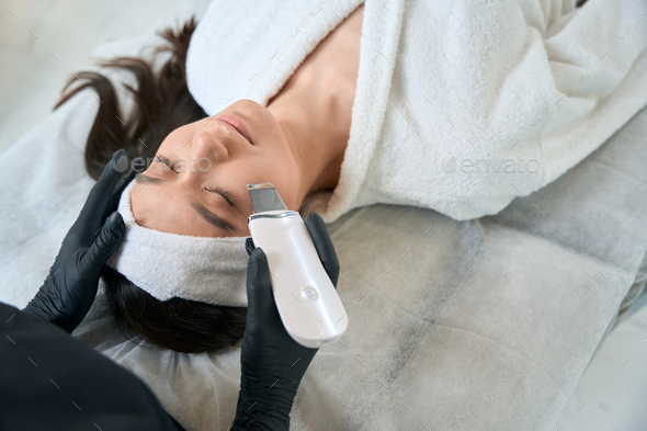 Dermatologist holding instrument and cleaning skin, working in salon ...