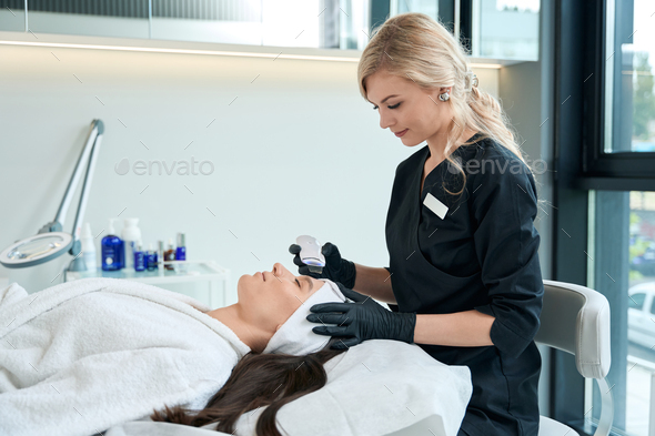 Nurse holding instrument and cleaning skin, working in salon Stock ...