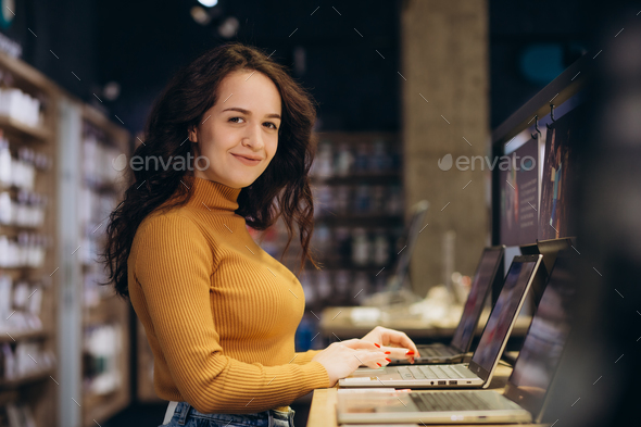 Smart modern female customer choosing laptop in the computer shop ...