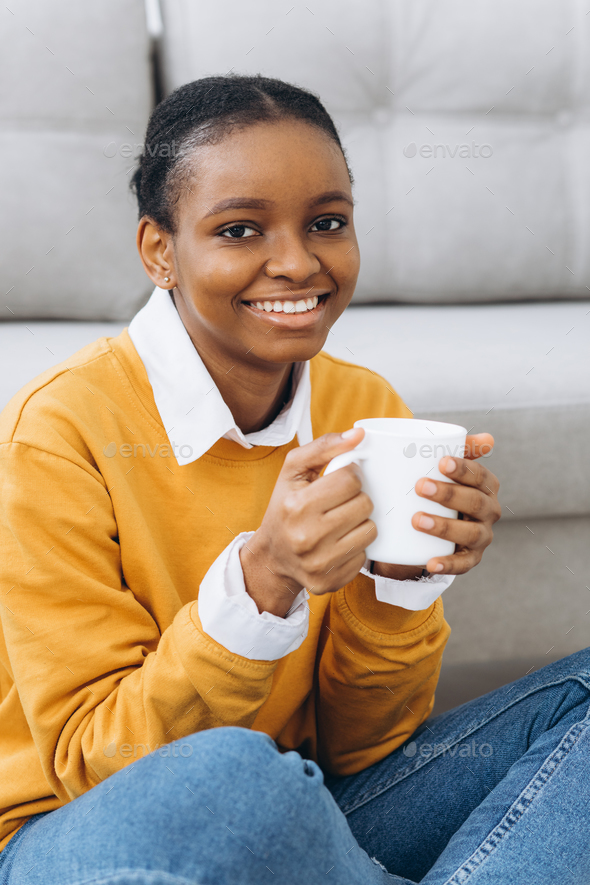 Beautiful young Black female university student sitting on the floor ...