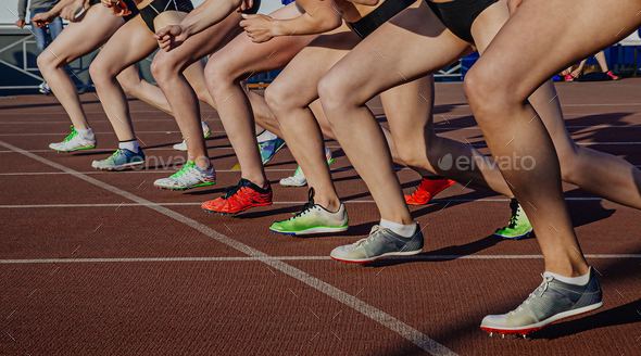 legs female athletes in running spikes shoes on starting line of middle ...