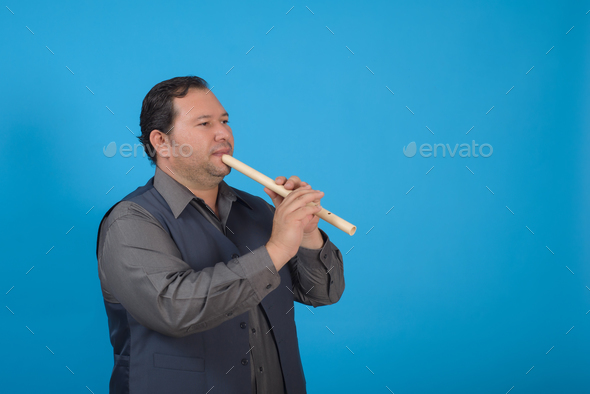 Studio portrait of a man playing a recorder. Blue background with copy ...