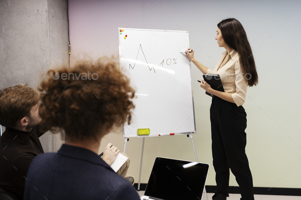 Attractive teacher woman explaining lecture to students, drawing graph ...