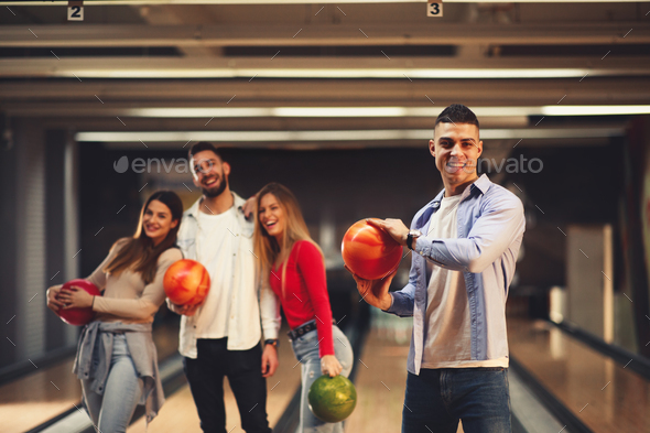 Beautiful group of young people posing in a bowling alley with a ball ...