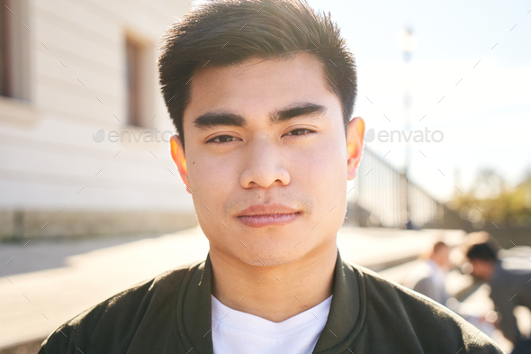 Outdoor portrait of an Asian man looking at the camera with a serious ...