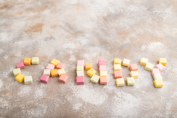 The inscription "candy" laid out with fruit chewing candies on brown ...