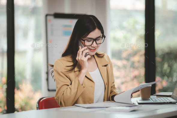 Asian woman talking on the phone, she is a salesperson in a startup ...