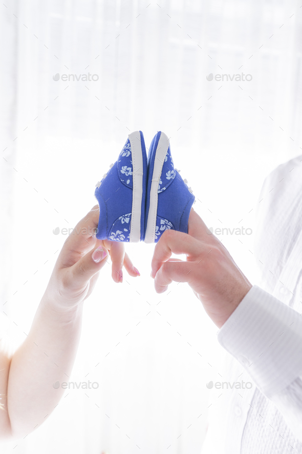 the woman's hand and the man's hand hold small shoes on their fingers ...