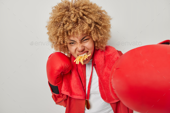 Professional curly female boxer poses with mouth full of fried crisps ...
