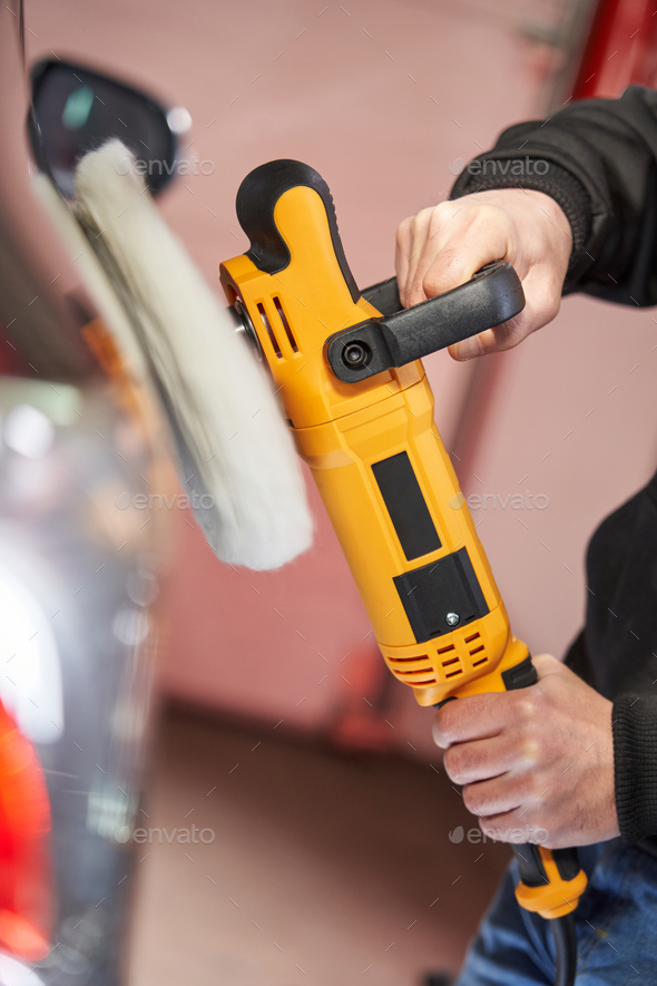 caucasian worker's hands hold the handles of a yellow angle grinder ...