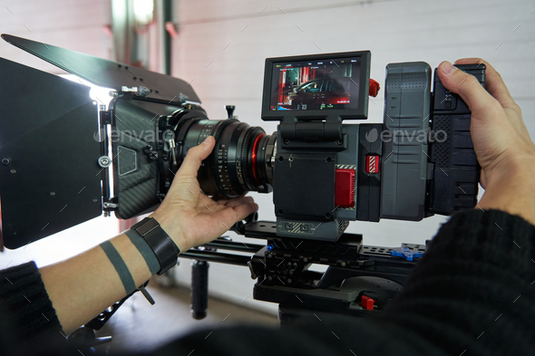 Man's hands control a professional movie camera through the monitor ...