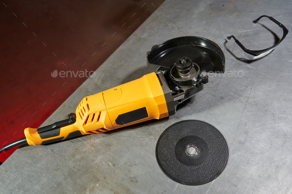yellow beautiful angle grinder, cutting disc and goggles lie side by ...