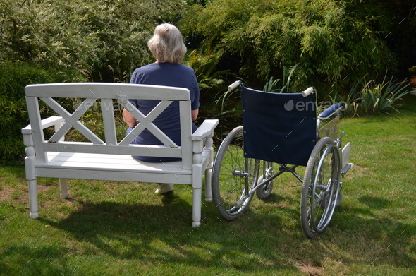 Old woman sitting on a white bench with a wheelchair next to her Stock ...