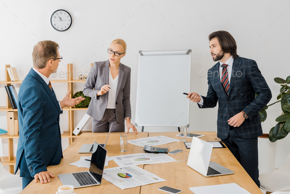 business people standing near table and having discussion in office ...