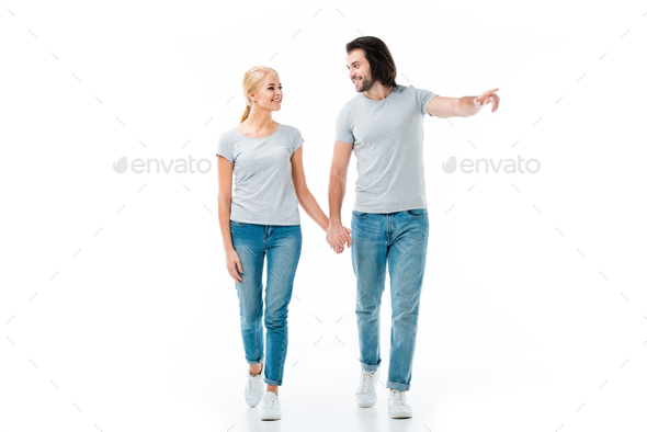 Beautiful smiling couple holding hands while man pointing at something ...