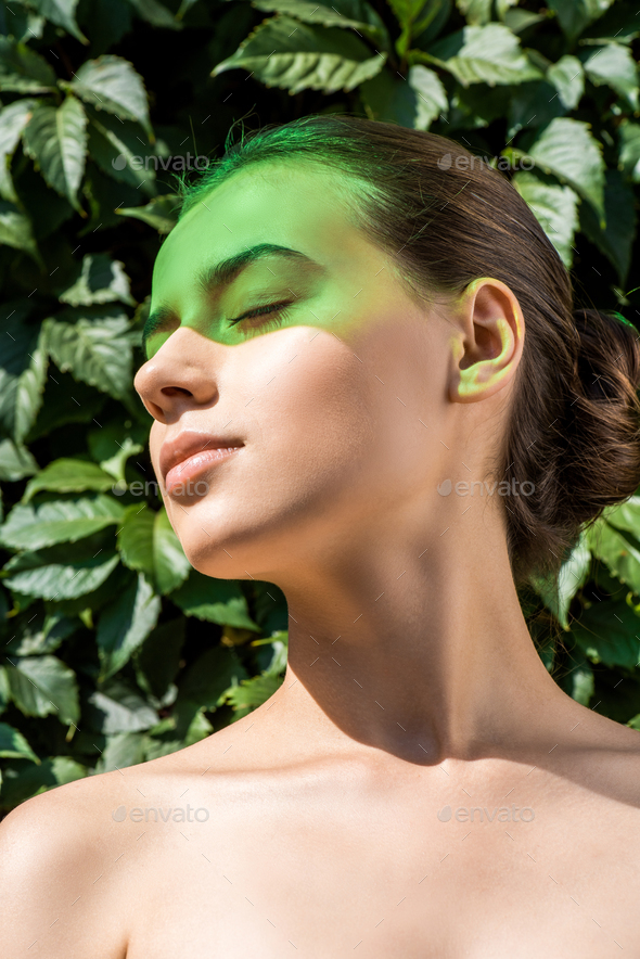 young woman with green shadow on face and leaves at background Stock ...