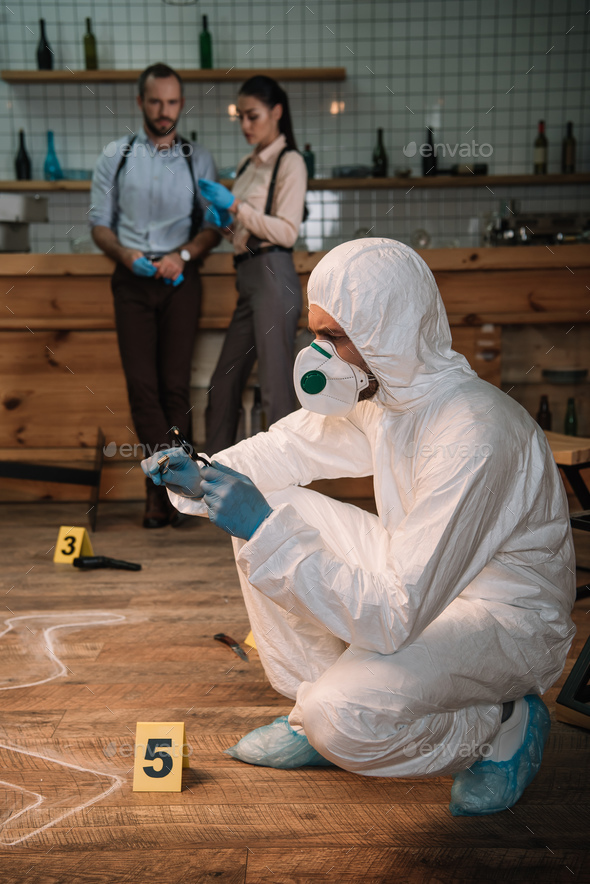 concentarted forensic investigator examining evidence with magnifying ...